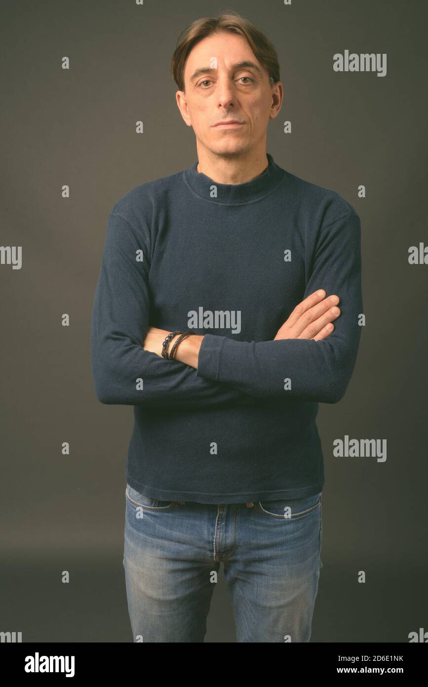 Mature handsome Italian man against gray background Stock Photo - Alamy