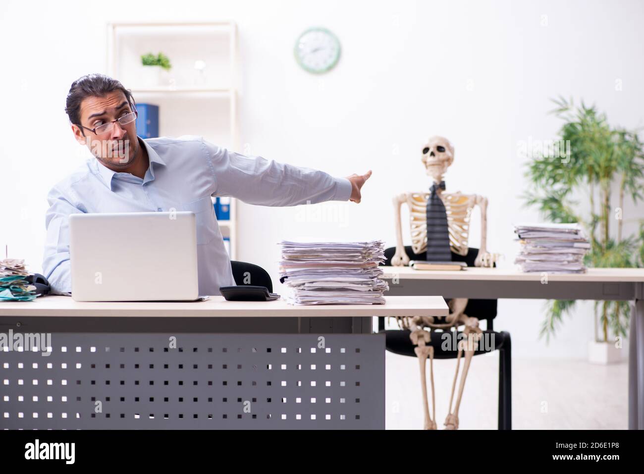 Young employee and skeleton in the office Stock Photo - Alamy