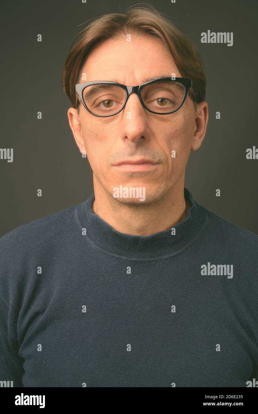 Mature handsome Italian man against gray background Stock Photo - Alamy