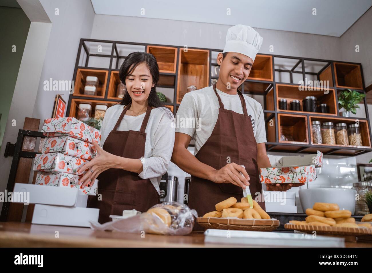 Young couples making bakery donuts in the kitchen at the bakery shop as ...