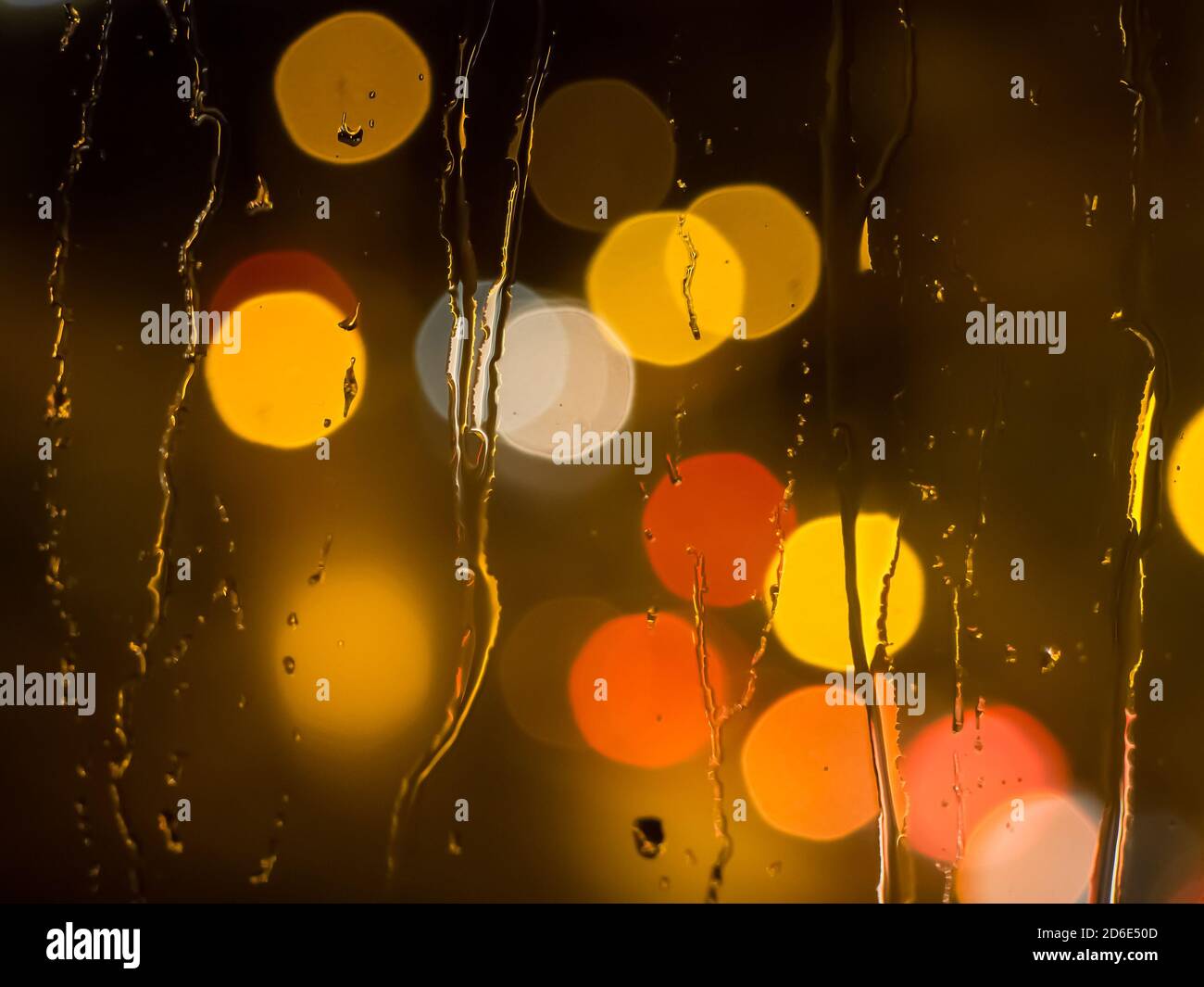 Raindrops and water trickling down a window pane with defocused street ...