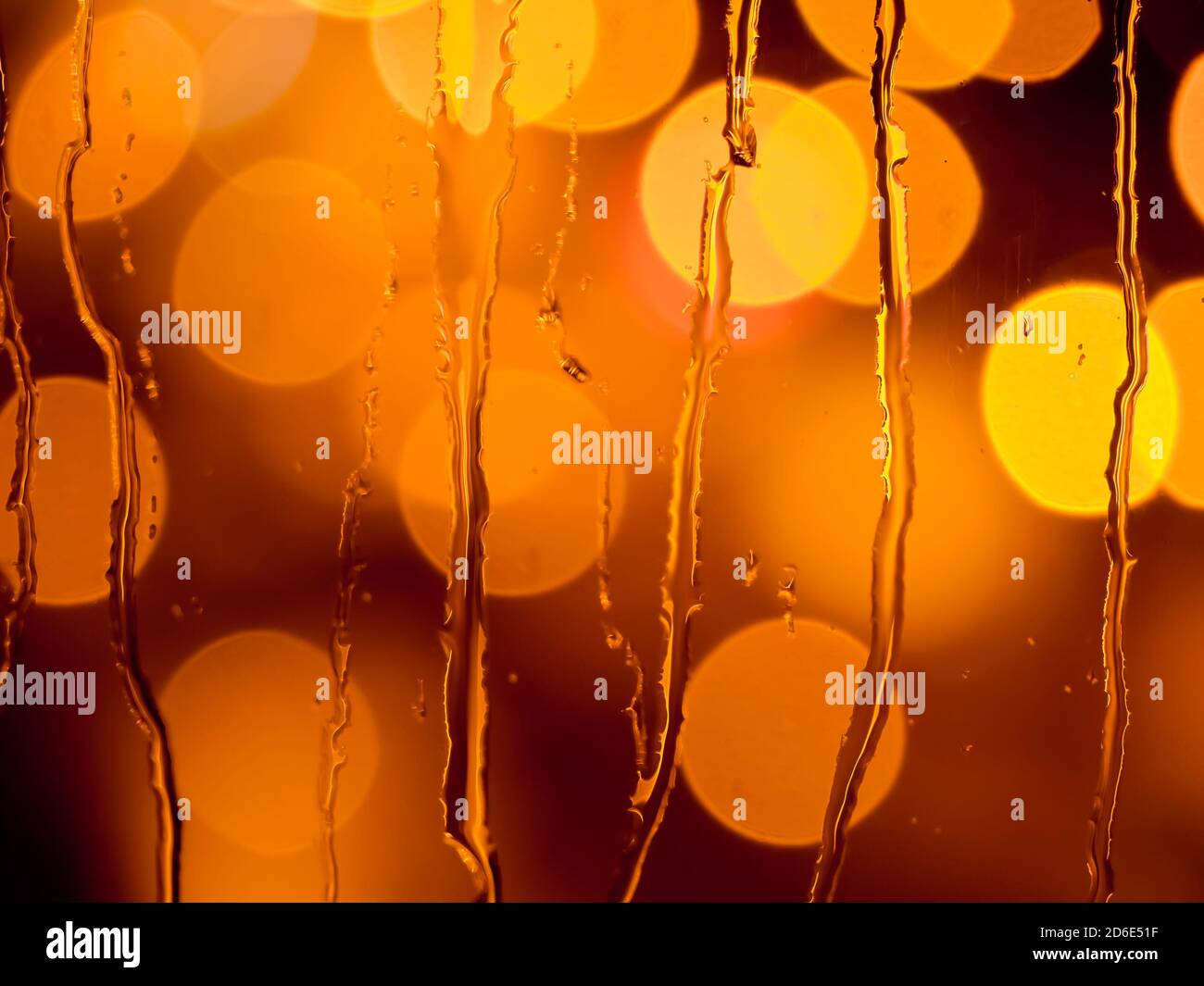 Raindrops and water trickling down a window pane with defocused street ...
