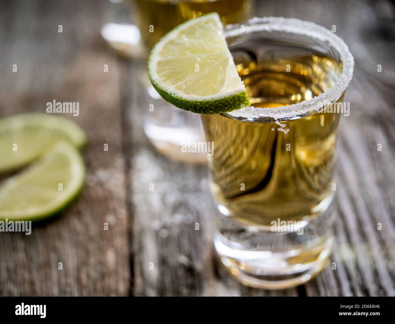 Tequila shots served with salt rim and lime wedges on a grunge wooden ...