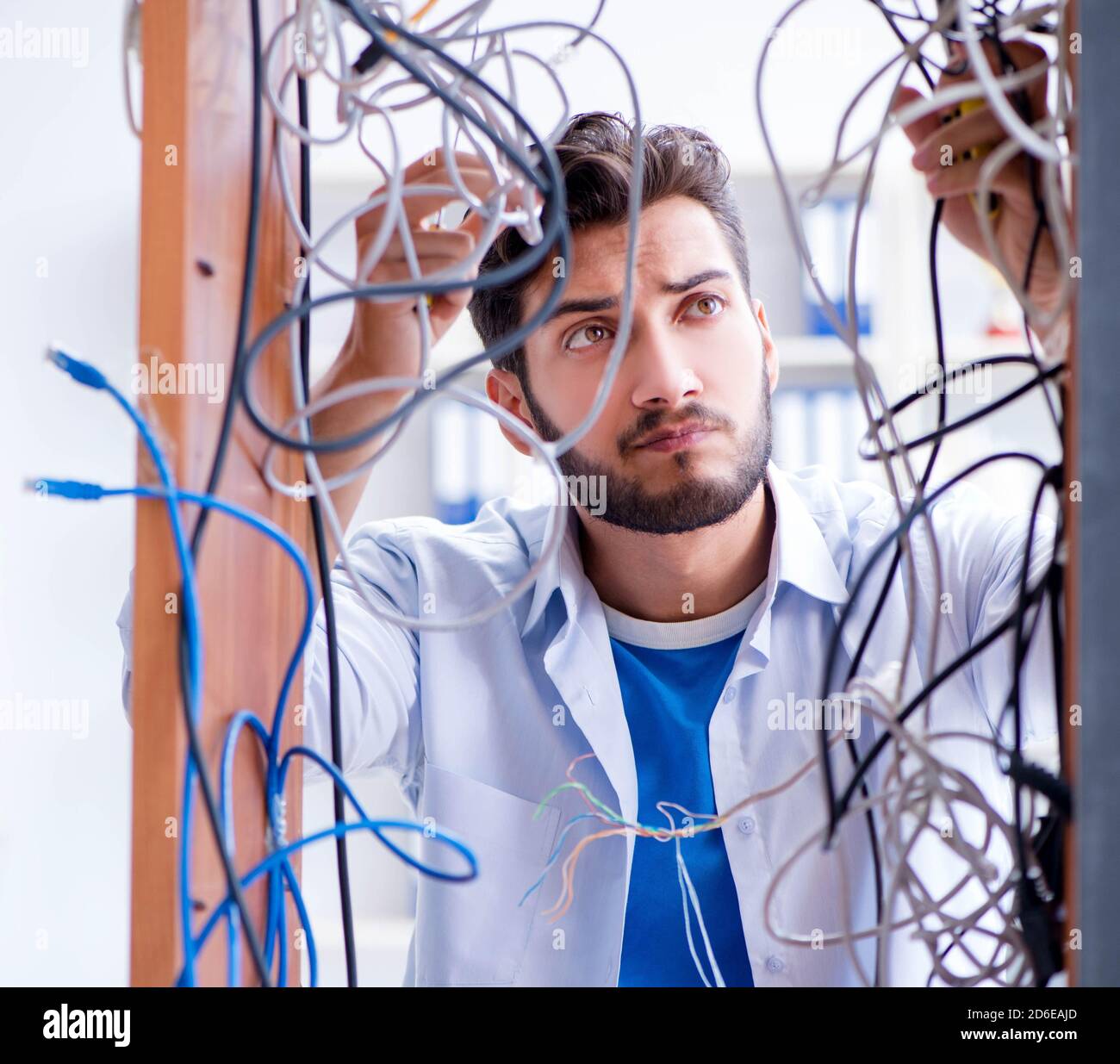The electrician trying to untangle wires in repair concept Stock Photo ...