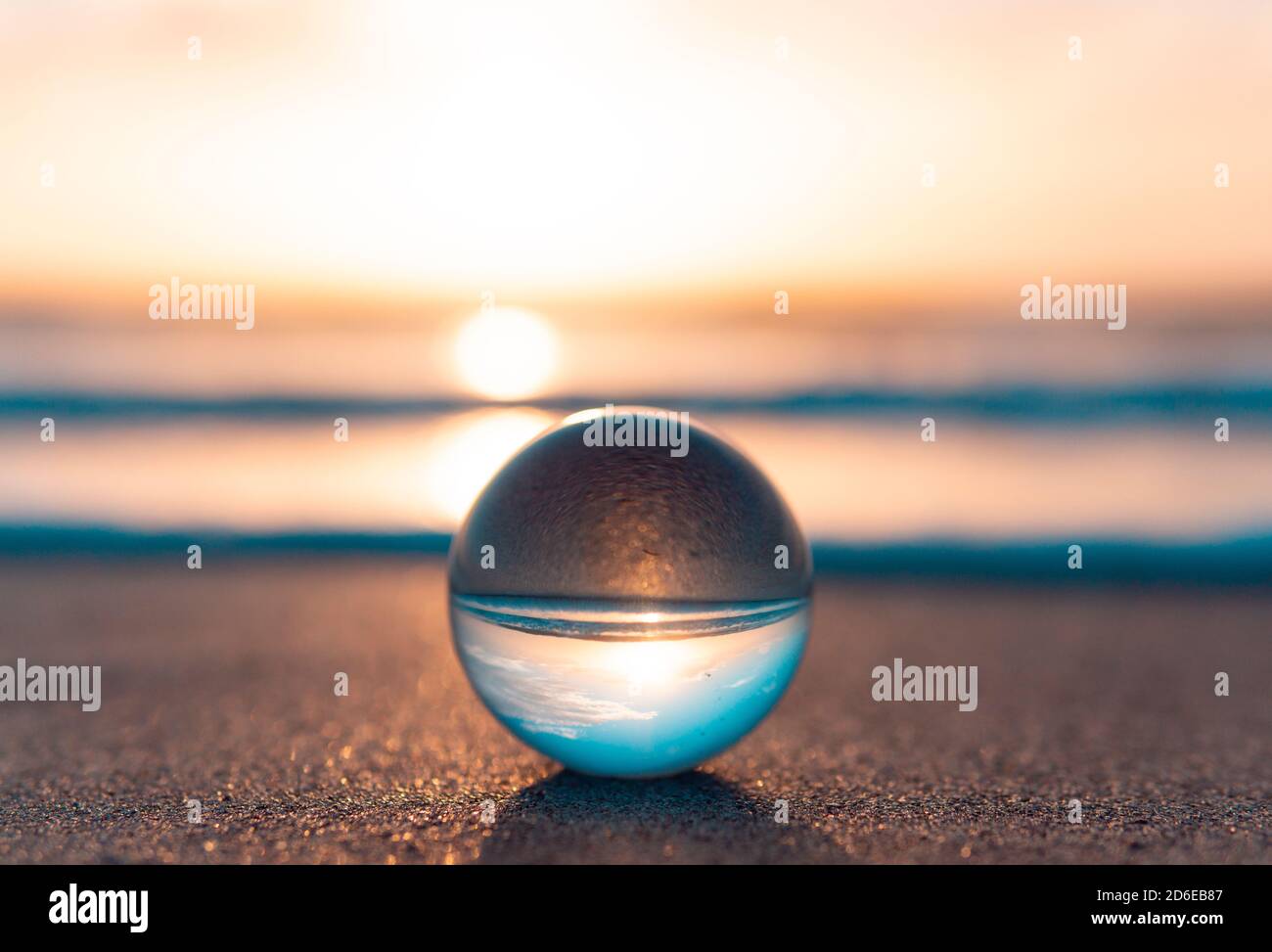 Beautiful artistic photograph of serene sunrise glass ball on sandy ...