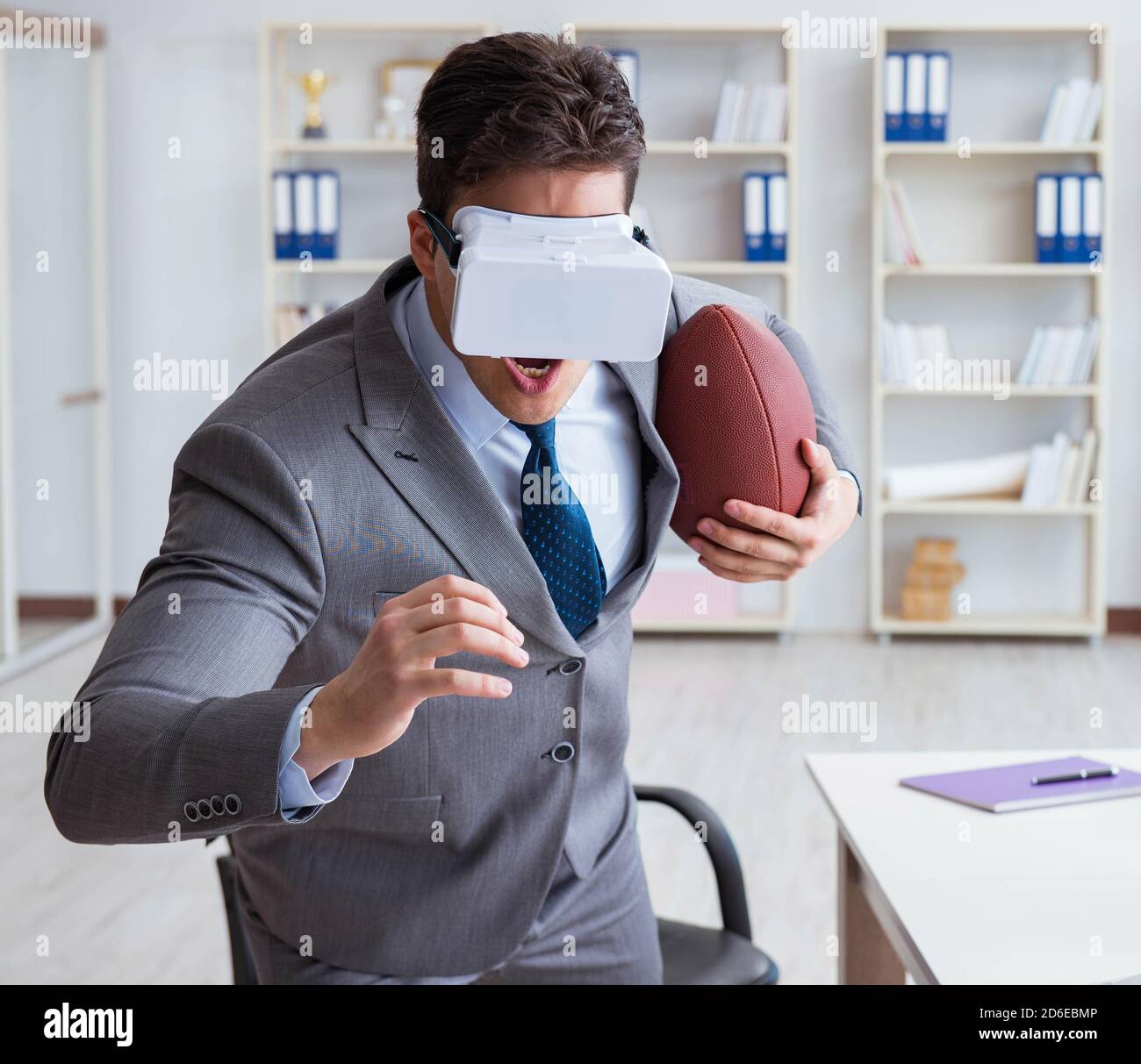 Businessman playing virtual reality football in office with VR goggle ...