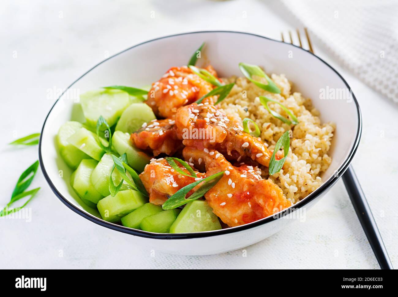 Fish fillet cooked in tomato sauce with bulgur and cucumber on a plate ...