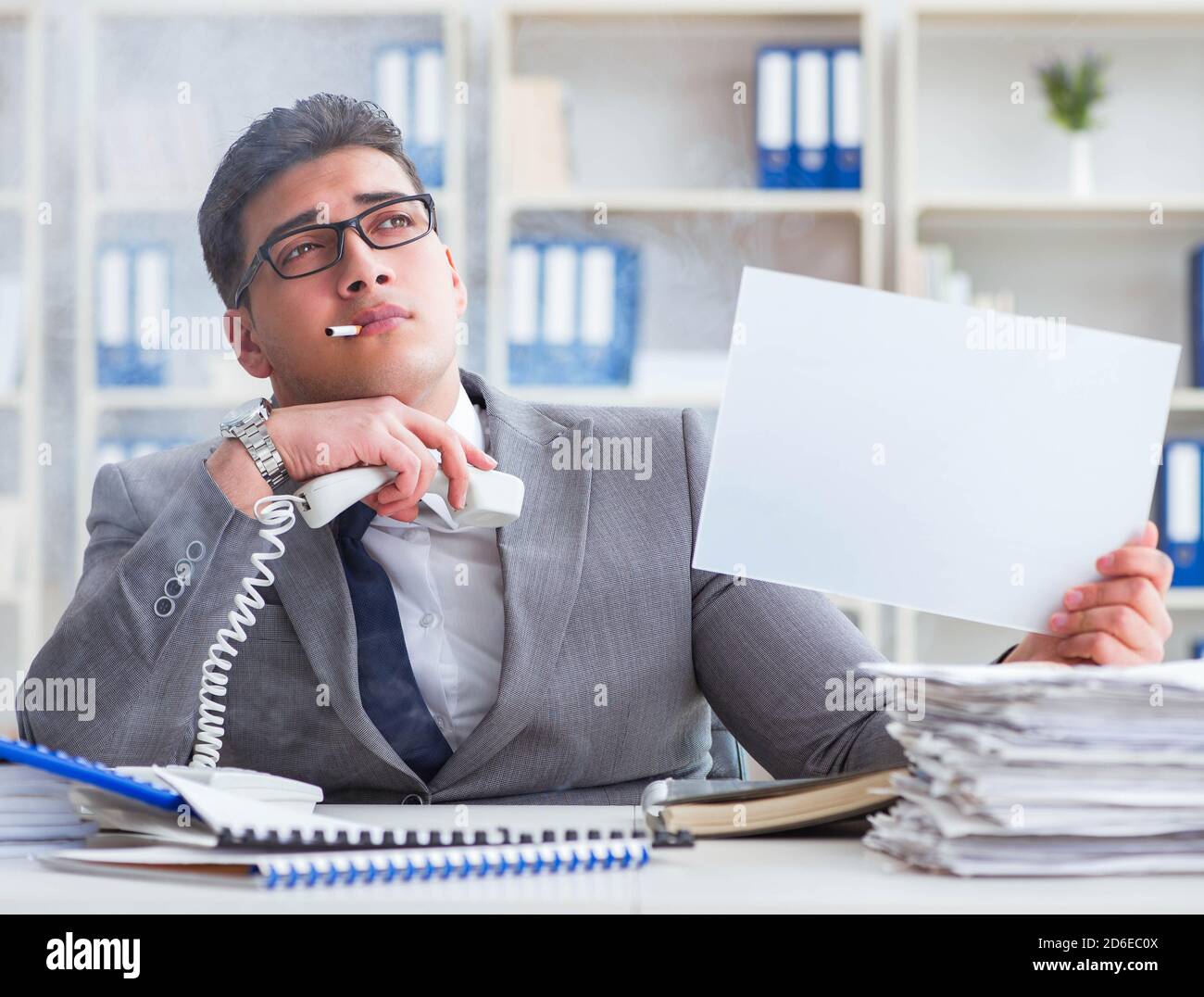 Businessman smoking at work in office holding a blank message board ...