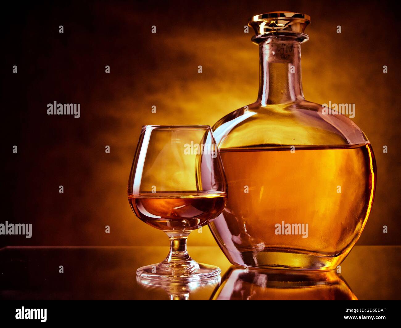 Bottle and glass of brandy on a dramatic red and yellow background ...