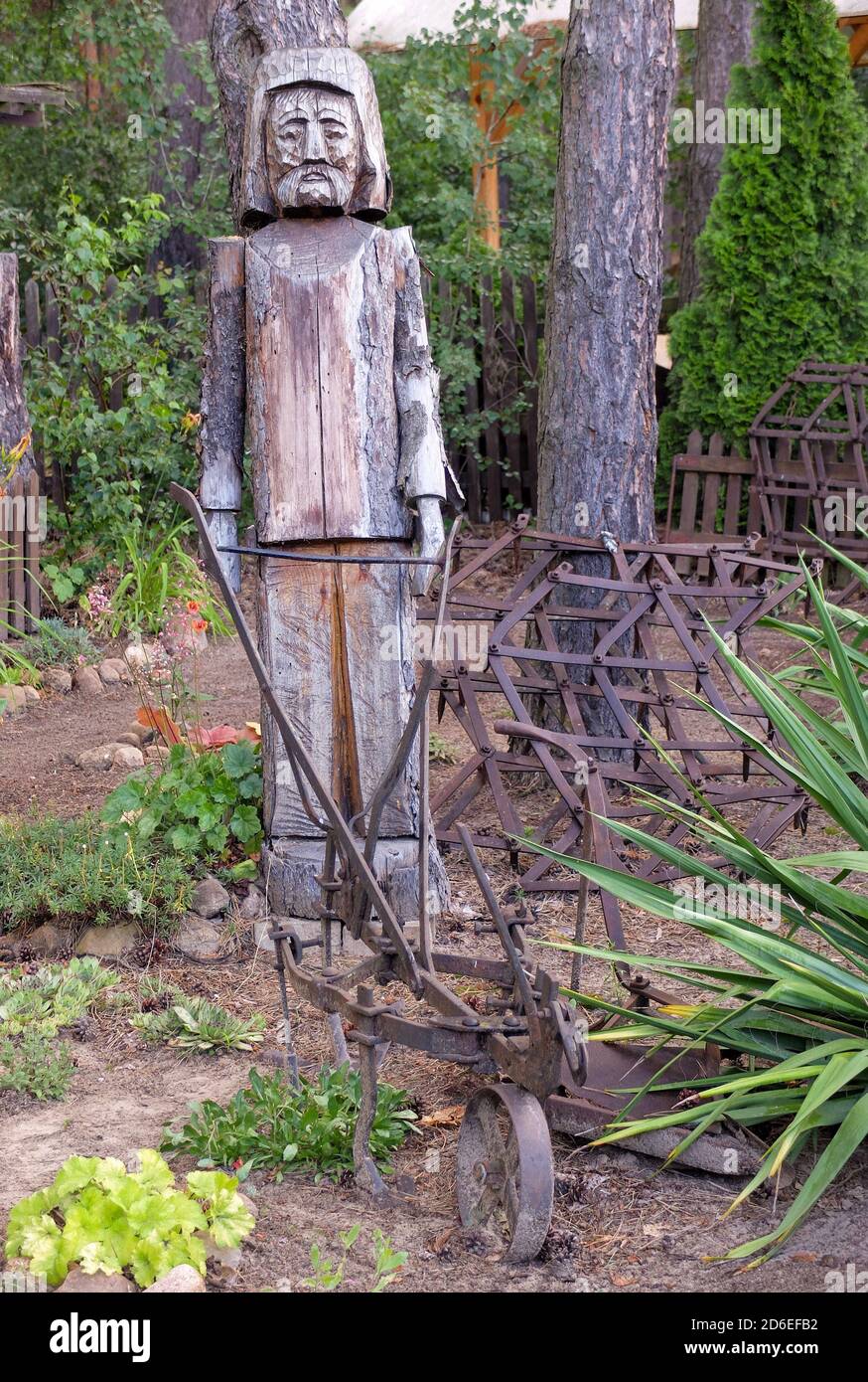 Carved wooden figure in the garden - farmer with old tools Stock Photo ...