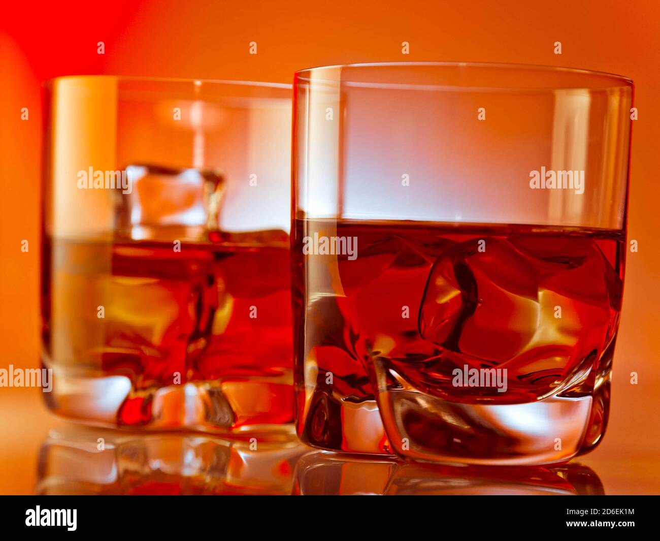 Two glasses of whiskey on the rocks over red background Stock Photo - Alamy