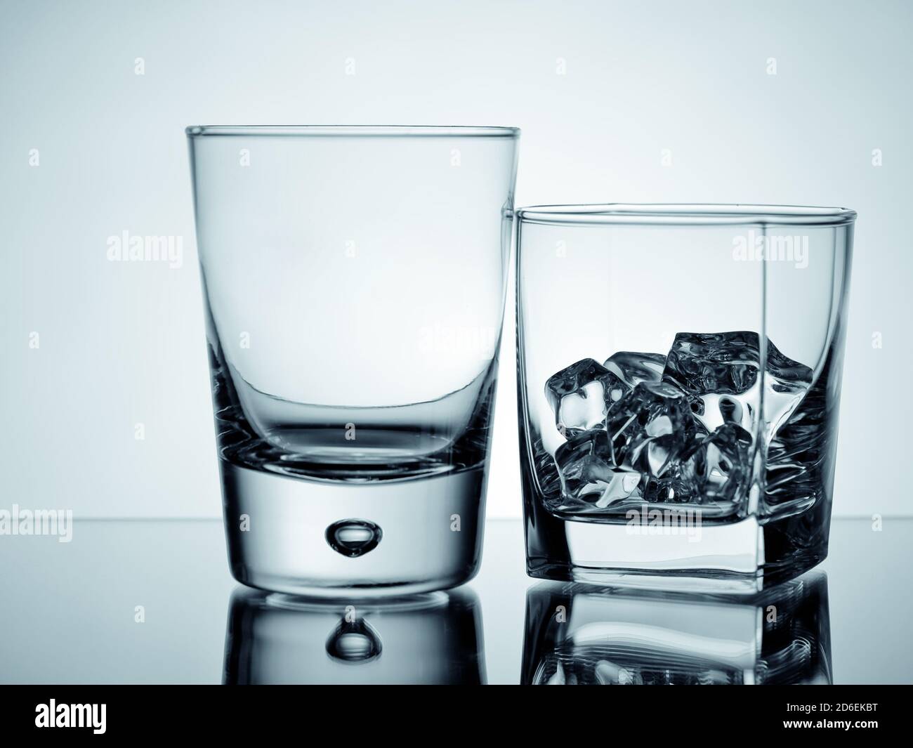 An empty glass and a tumbler with ice cubes Stock Photo - Alamy