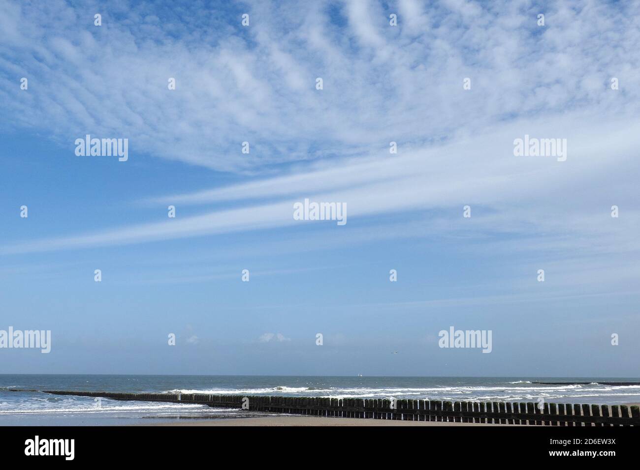 Beautiful scenery of a wooden dock on the beach under a cloudy sky ...