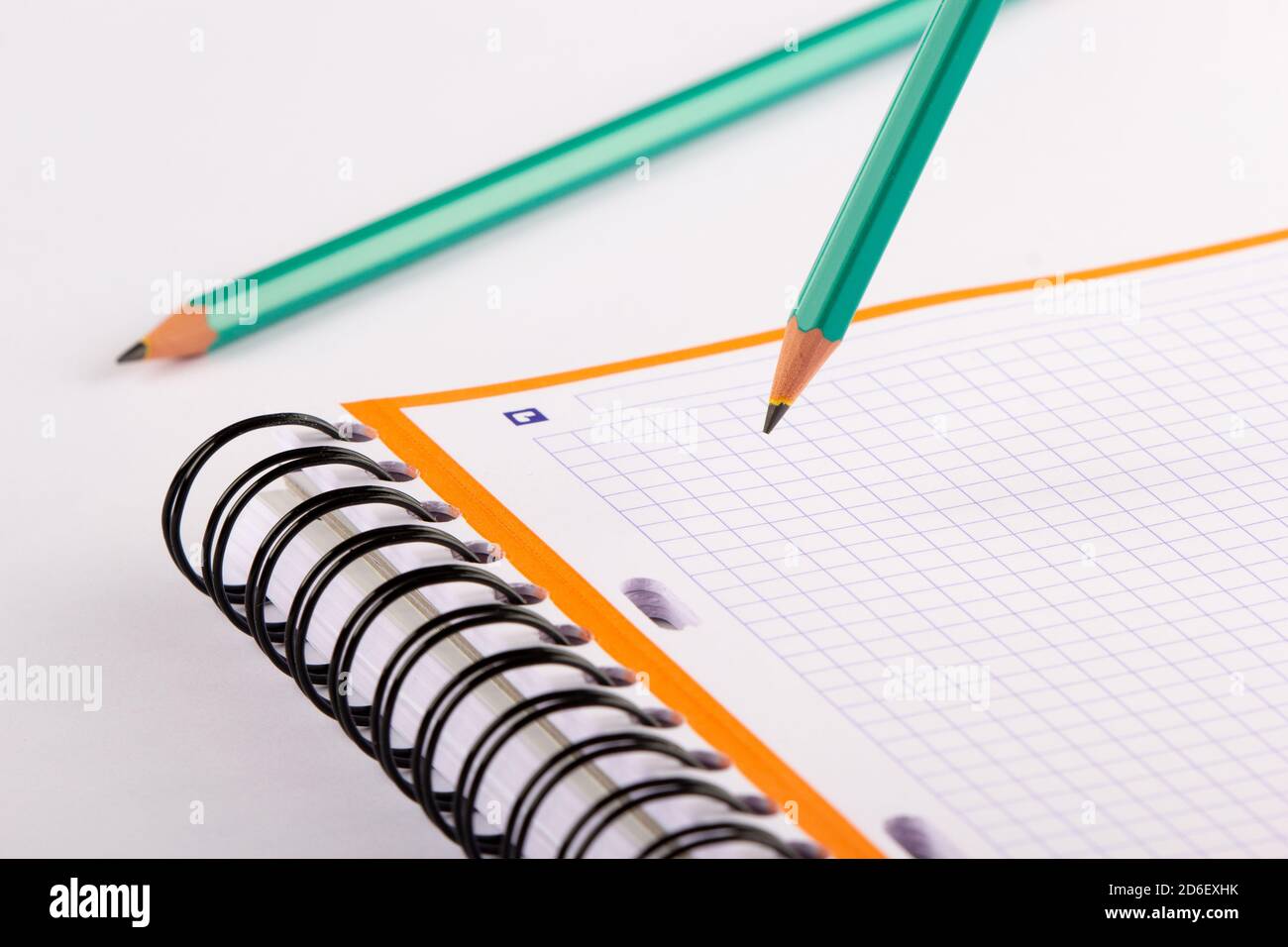 Green pencil writing in a checkered notebook. A card with an orange ...