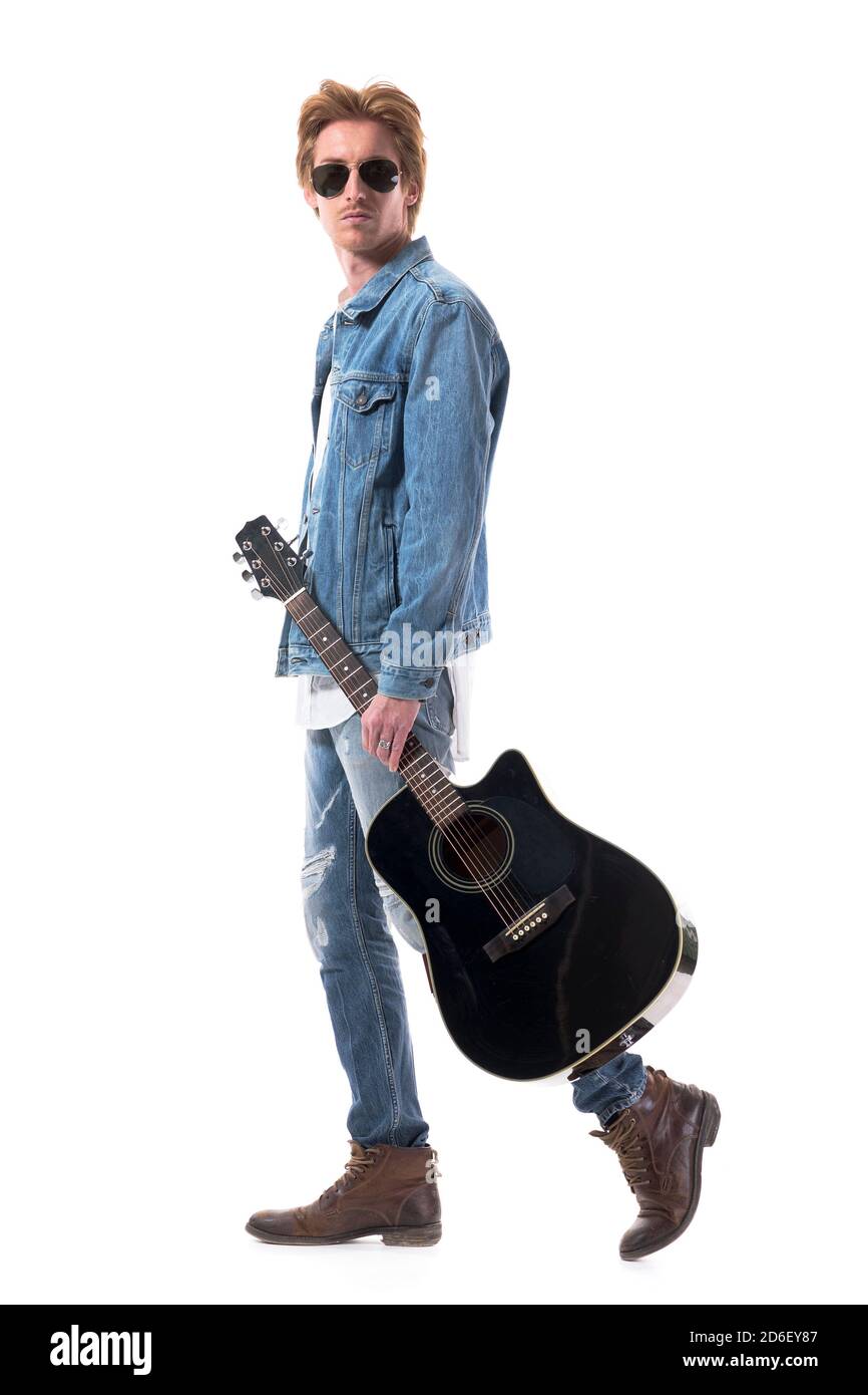 Profile view of cool confident man in jeans with sunglasses walking and ...