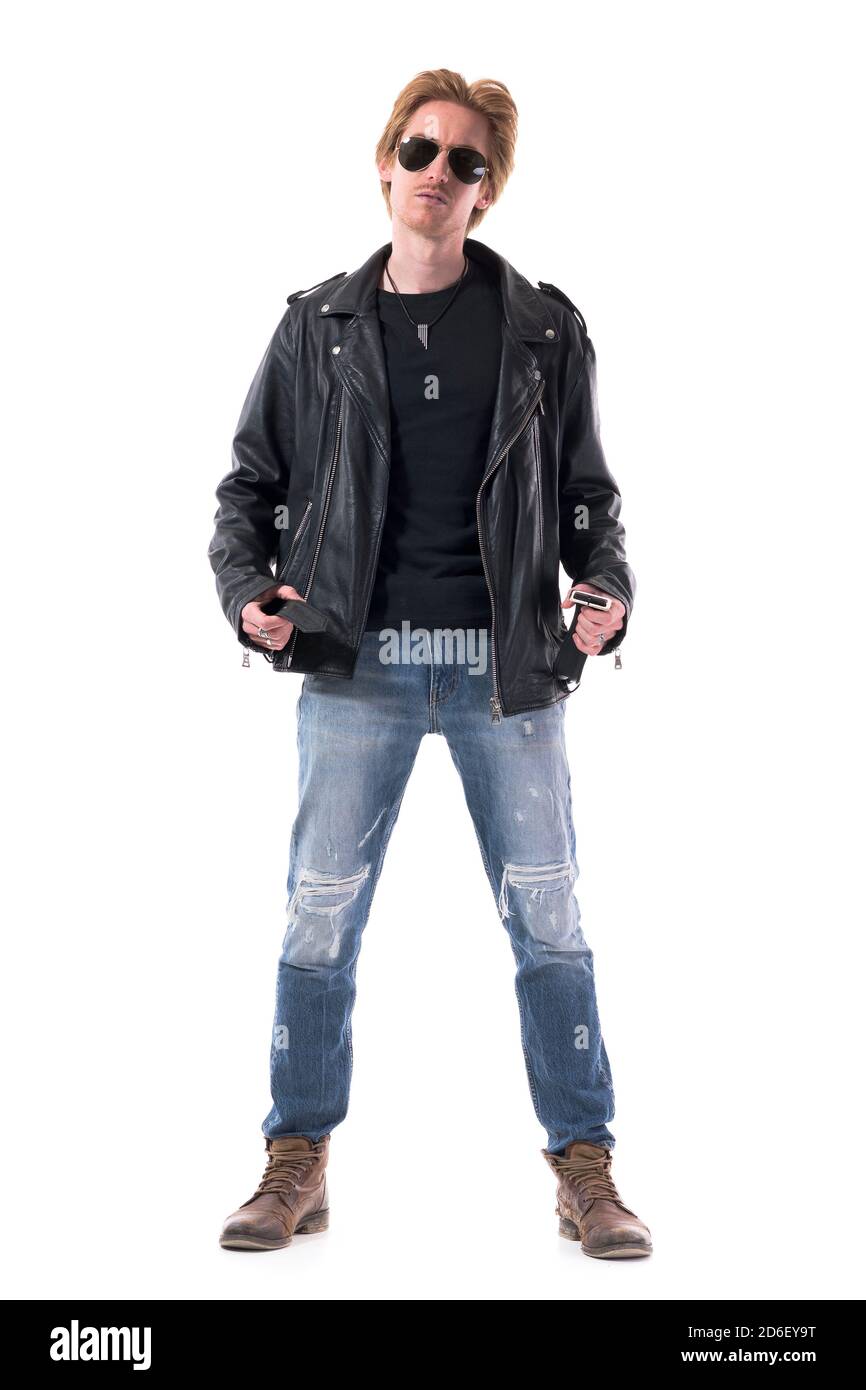 Serious young rocker style man in leather jacket and worn out boots ...