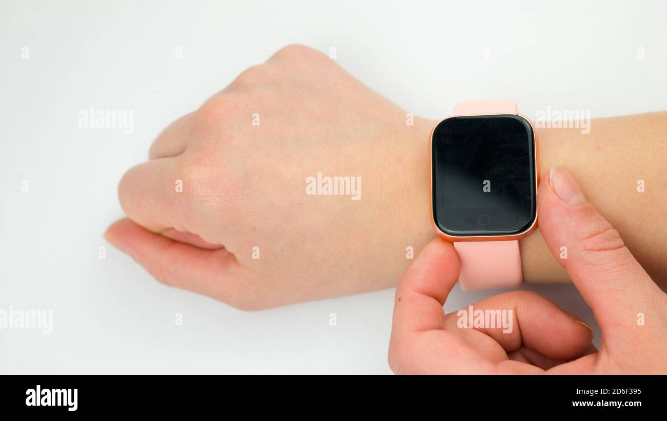 Woman's hand touching the screen of a smart watch on white background ...