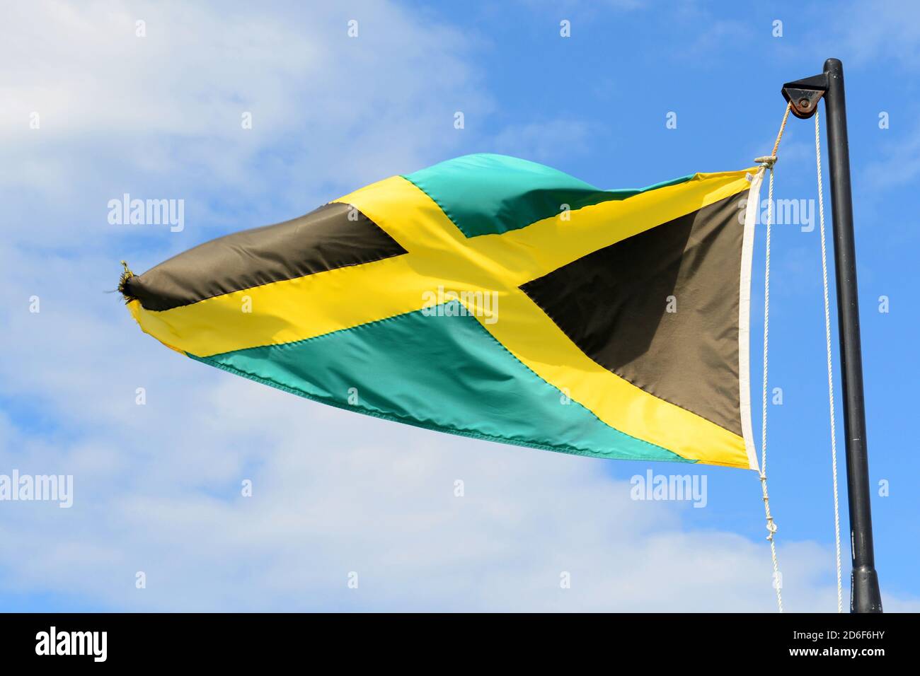 Flag of Jamaica waving against blue sky. Flag of Jamaica have a gold ...