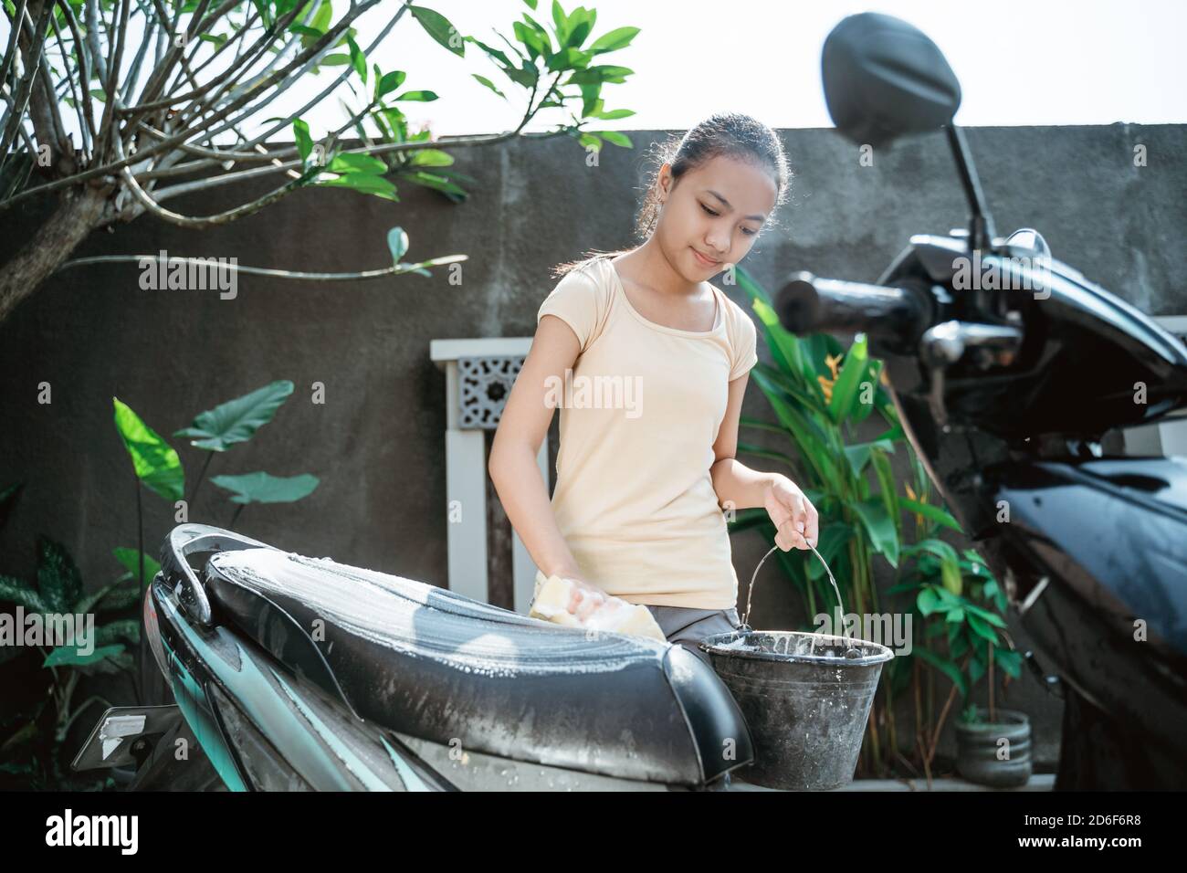 asian young girl washing his motorcycle scooter with soap and sponge at ...