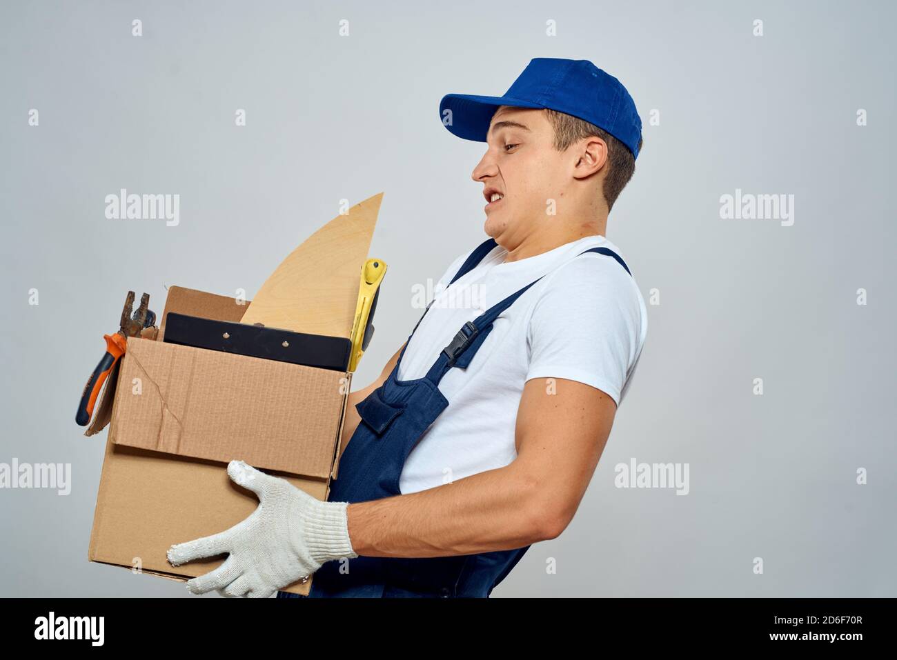 man in working uniform with a box in his hands tools loader delivery ...