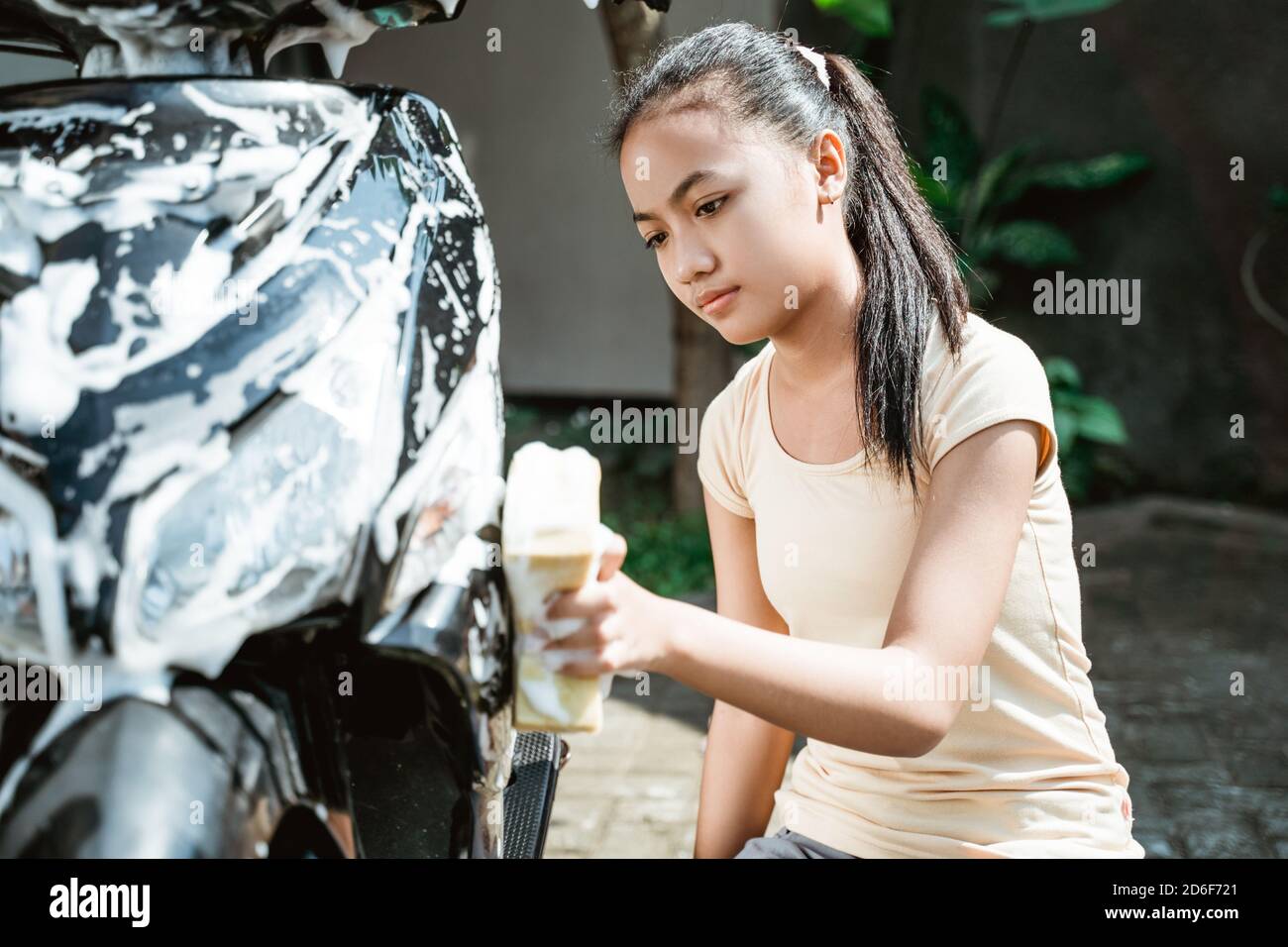 asian young girl washing his motorcycle scooter with soap and sponge at ...