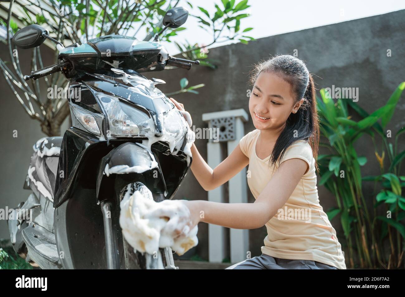 asian young girl washing his motorcycle scooter with soap and sponge at ...