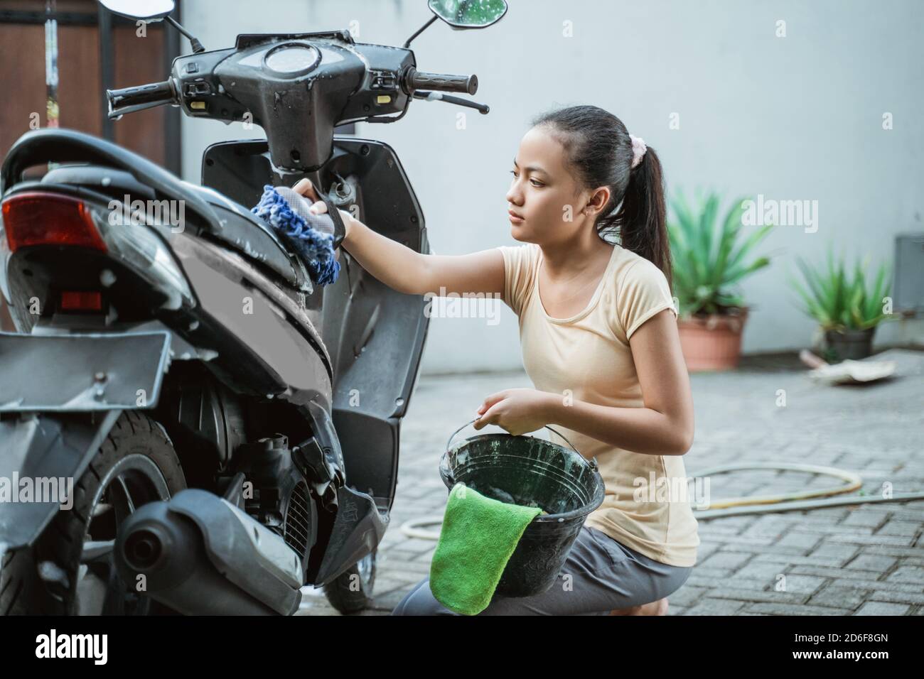 asian young girl washing his motorcycle scooter with soap and sponge at ...