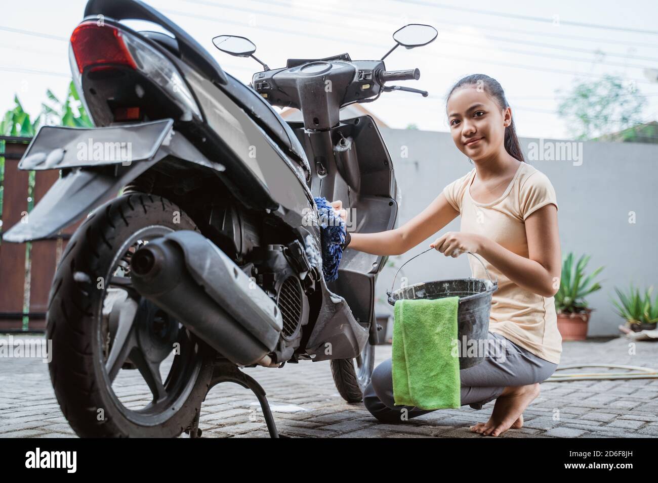 asian young girl washing his motorcycle scooter with soap and sponge at ...