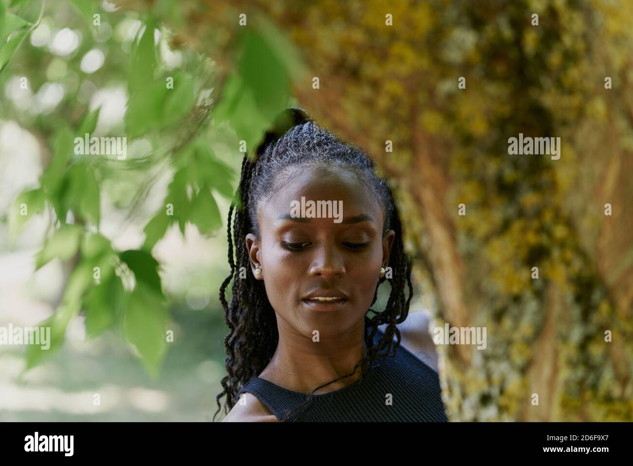 Portrait of beautiful black woman behind a tree Stock Photo - Alamy