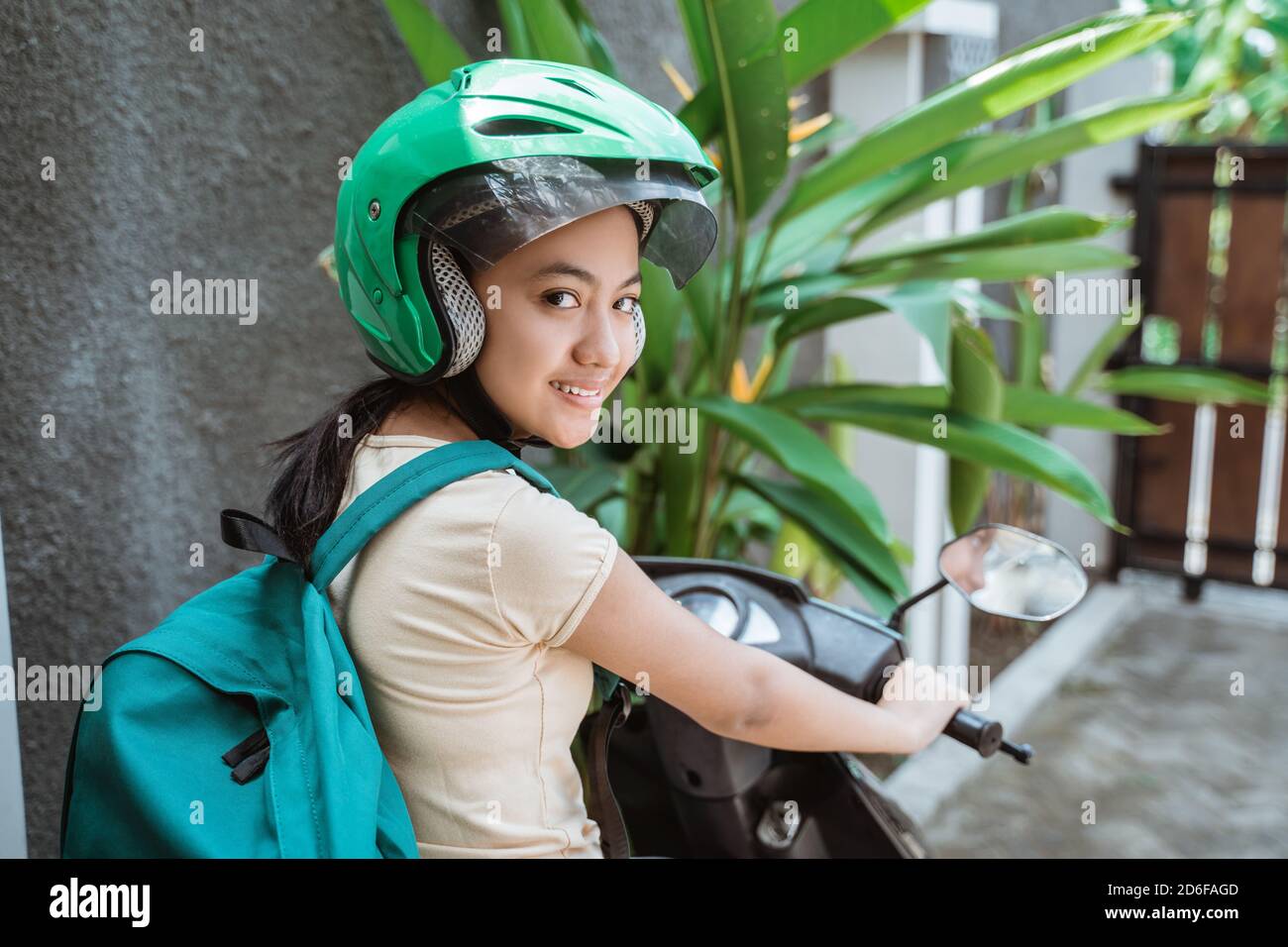 Beautiful young girl student is sitting on her motorcycle carrying ...