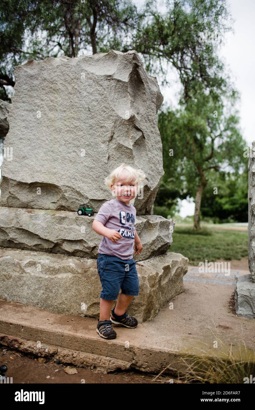 Two Year Old Smiling & Standing Next to Rock Stock Photo - Alamy