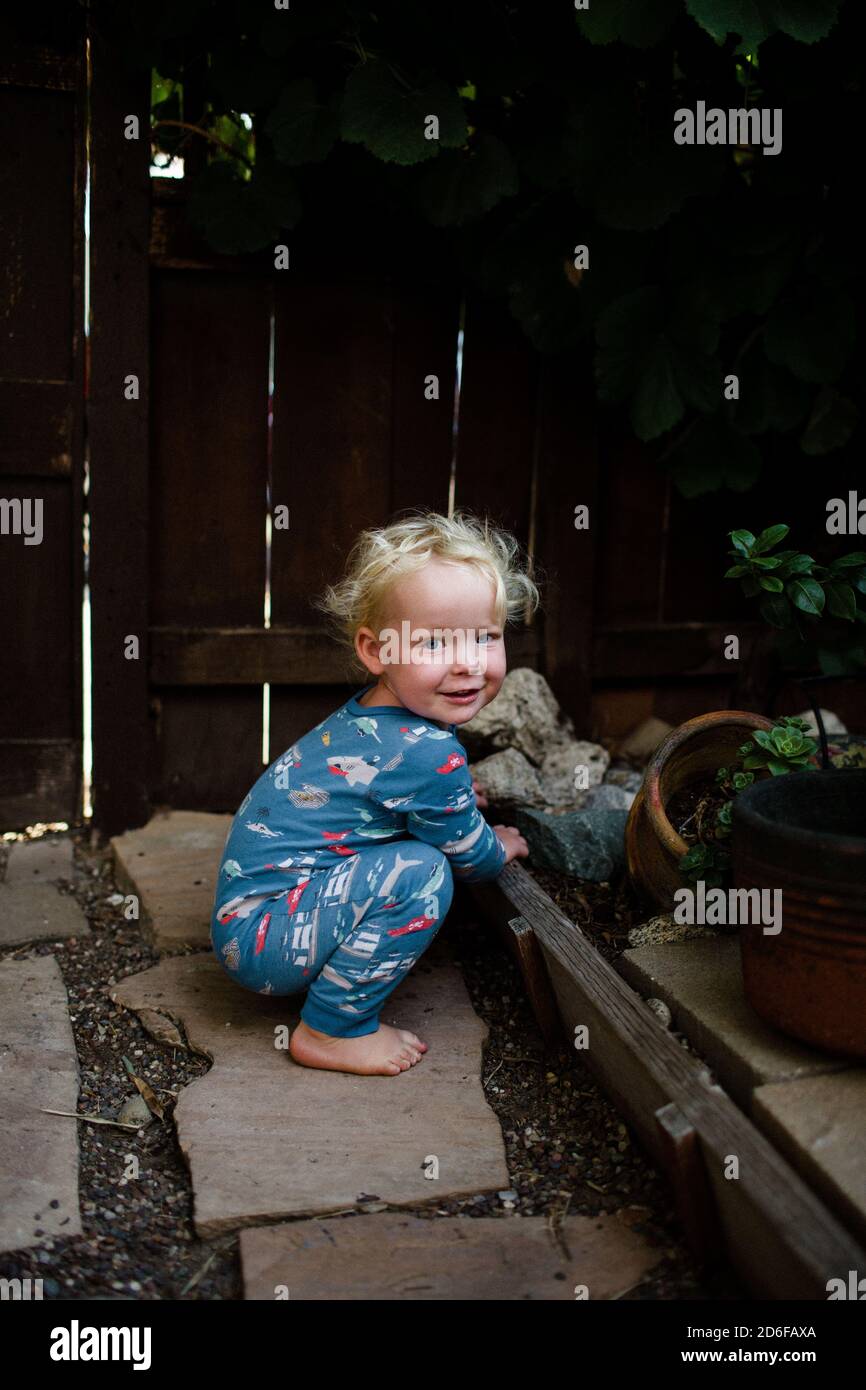 Two Year Old Smiling for Camera Crouching in Front Yard Stock Photo - Alamy