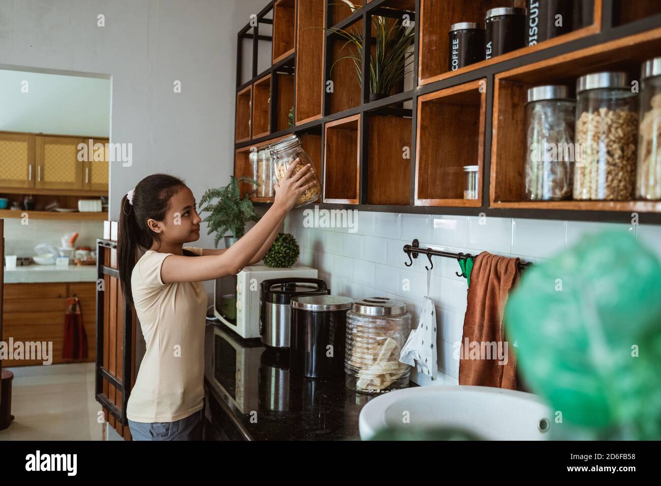 a beautiful young girl cleaning the kitchen tidying up kitchen item at ...