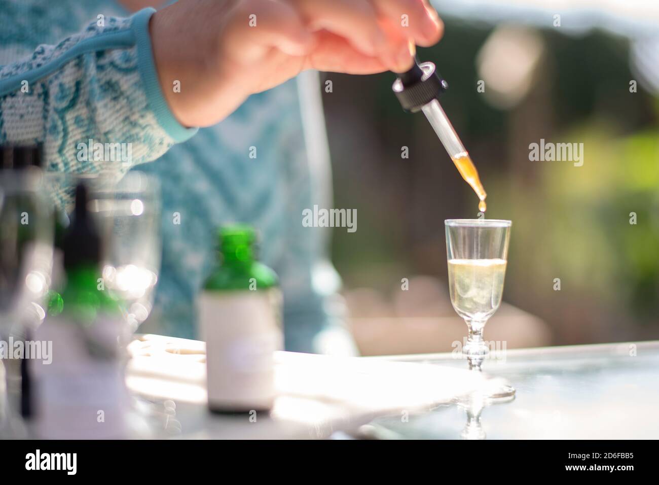 woman using dropper to add a tincture to a shot glass of water Stock ...