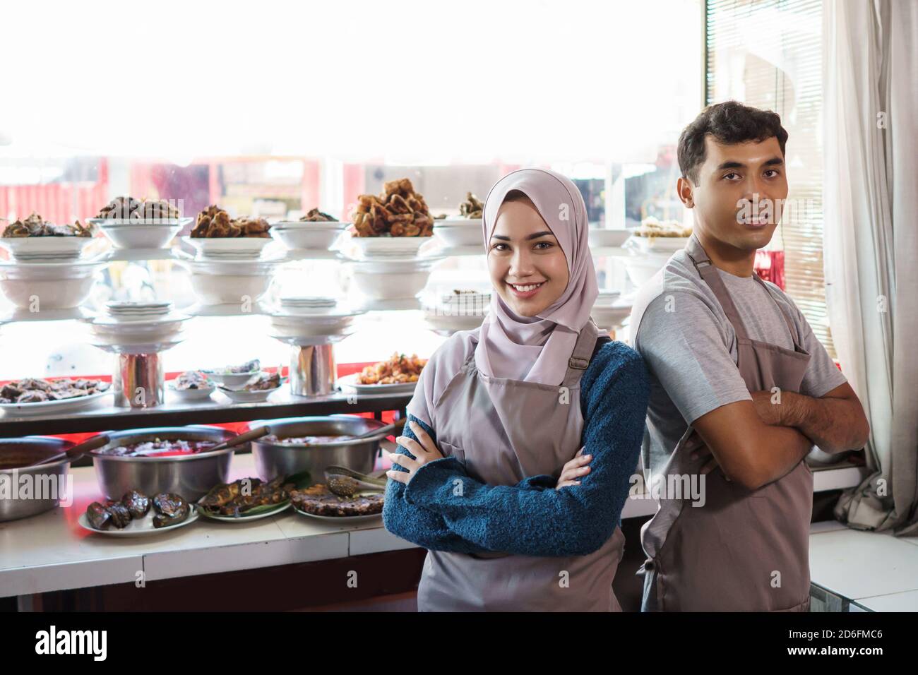 portrait of young man and female muslim working as traditional food ...