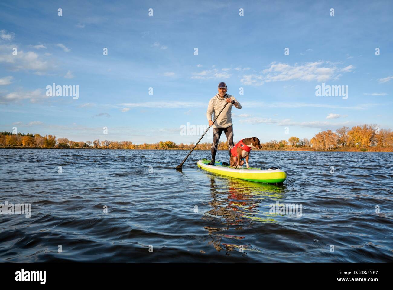 senior male is paddling an inflatable stand up paddleboard with a ...