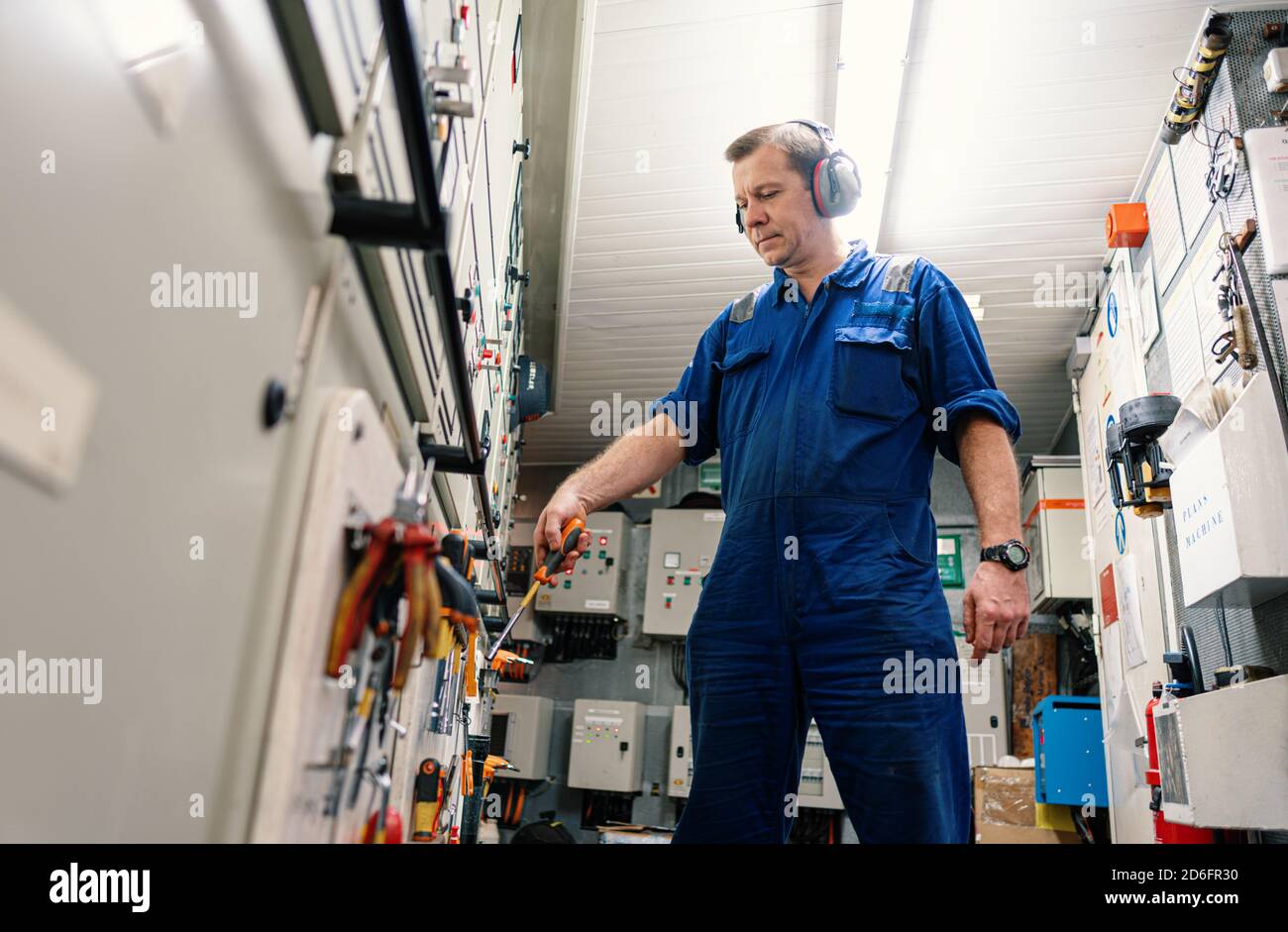 Marine engineer officer in engine control room ECR. He works in ...