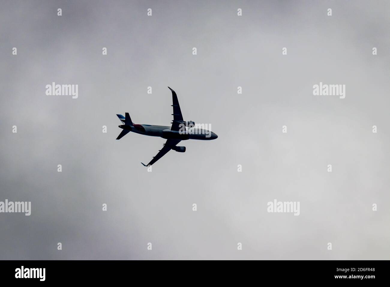 A passenger plane flies through the gray cloudy sky in bad weather ...