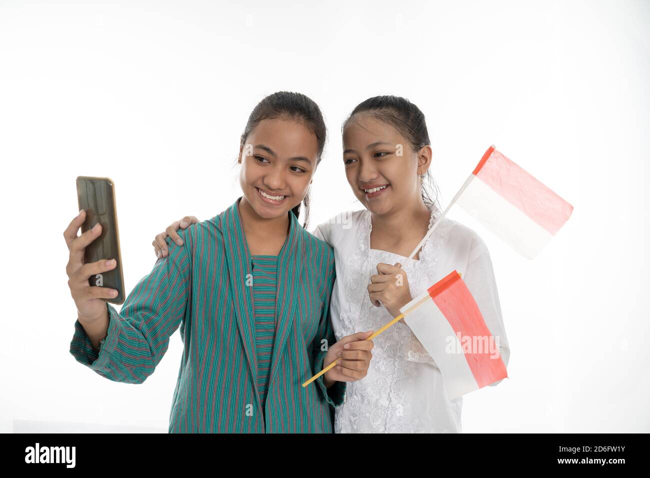 two teenager with indonesian kebaya using mobile phone together taking ...