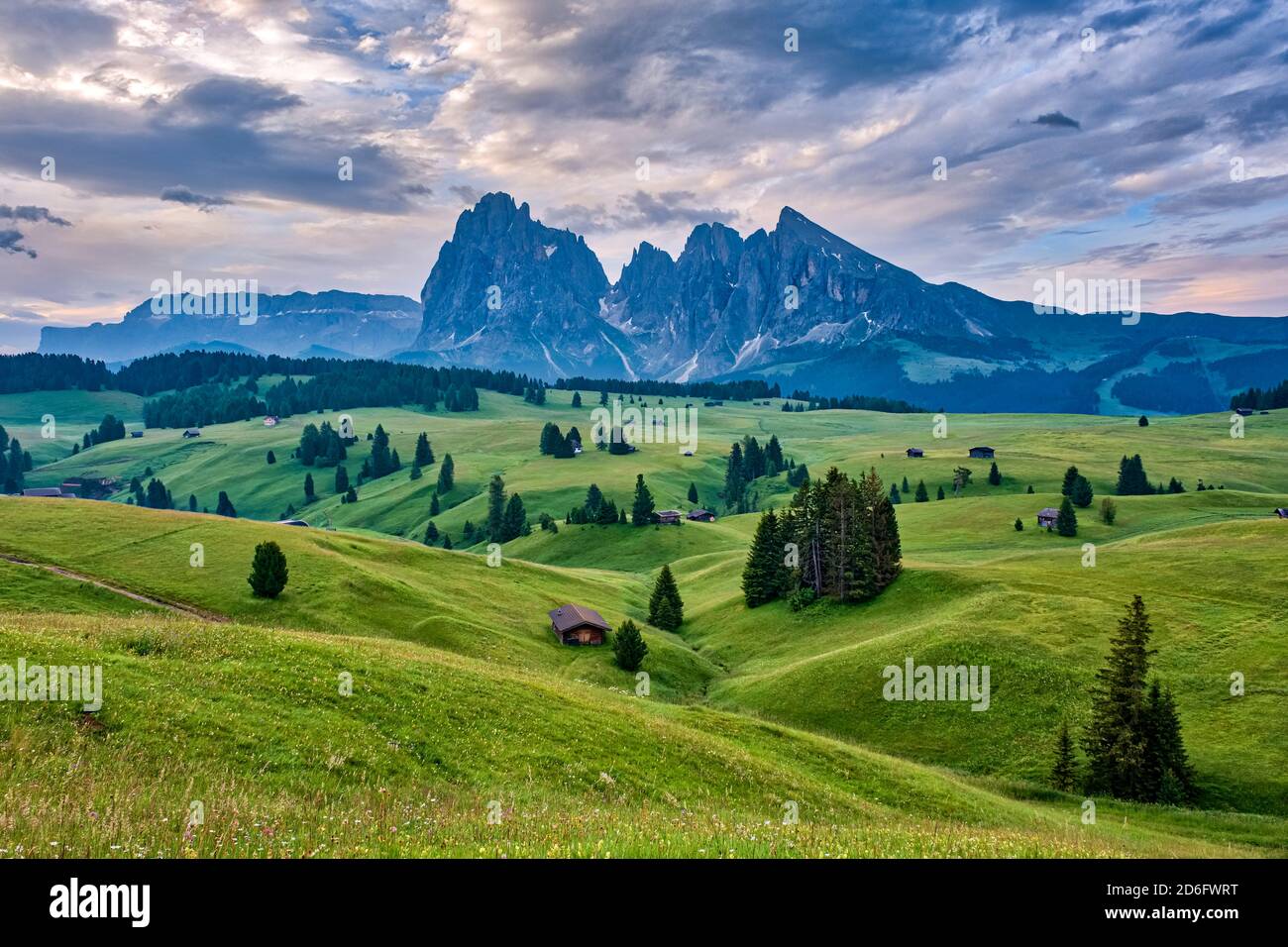 Hilly agricultural countryside with green pastures, trees and wooden ...