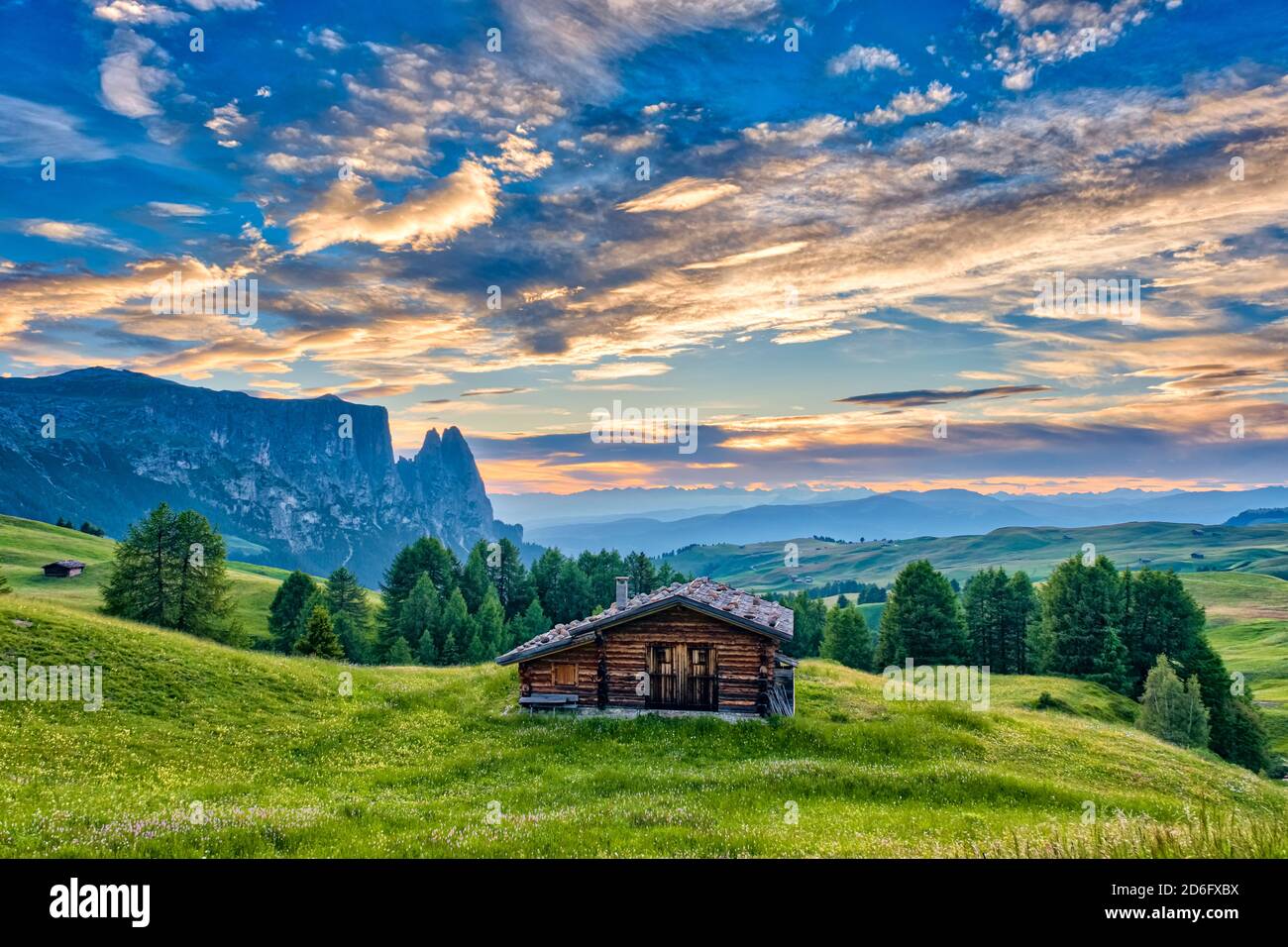 Hilly agricultural countryside with green pastures and a wooden house ...