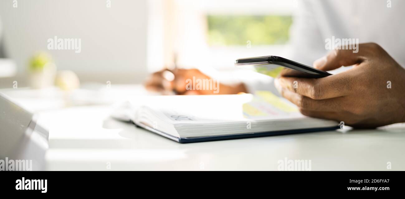 African Man Organizing Appointment Schedule Using Cellphone And ...