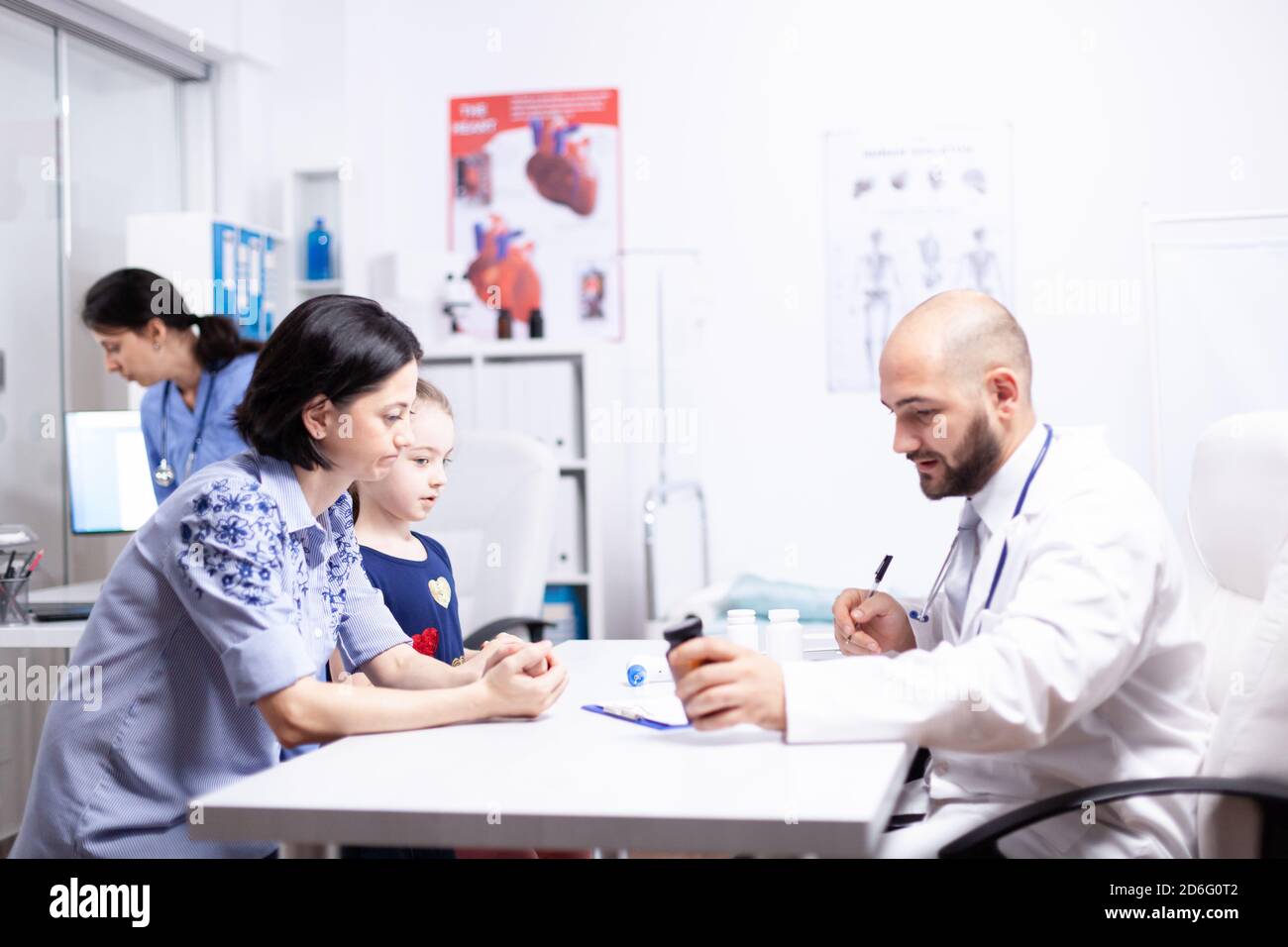 Doctor explaining treatment to mother of sick child in hospital office ...