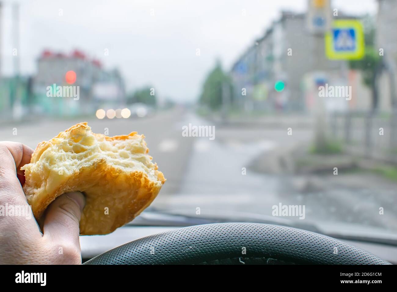 pie, bun, food in the hand of a driver at the wheel of a car who eats ...