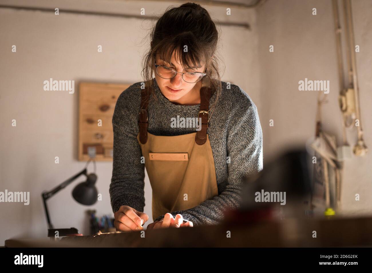 A young female carpenter drawing on a piece of timber while working ...