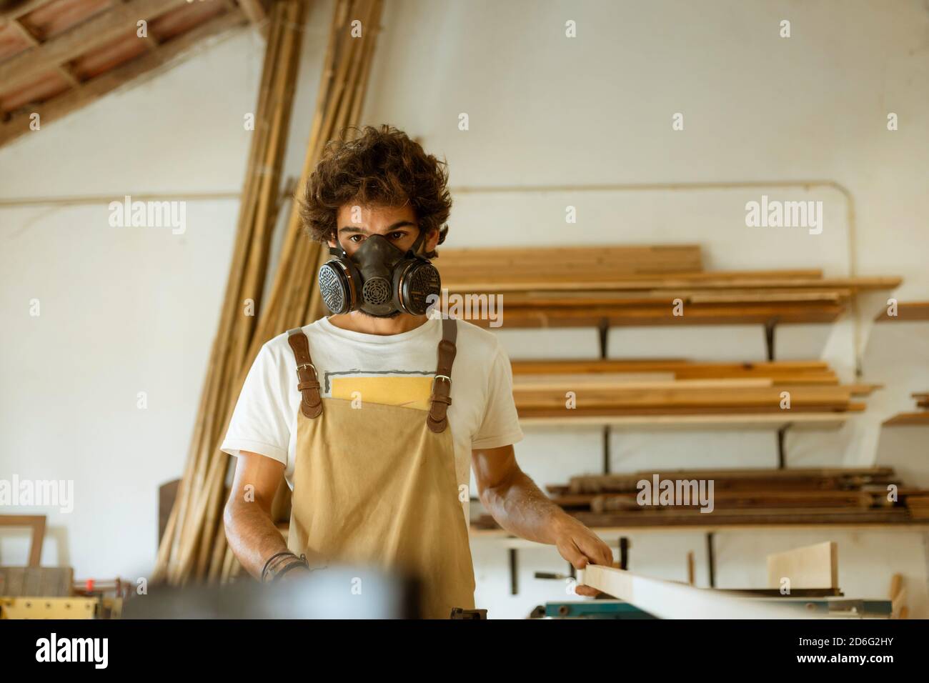 A young man working as carpenter in his wood workshop. Wood worker ...