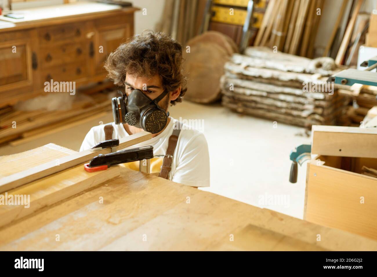 A young man working as carpenter in his wood workshop. Wood worker ...