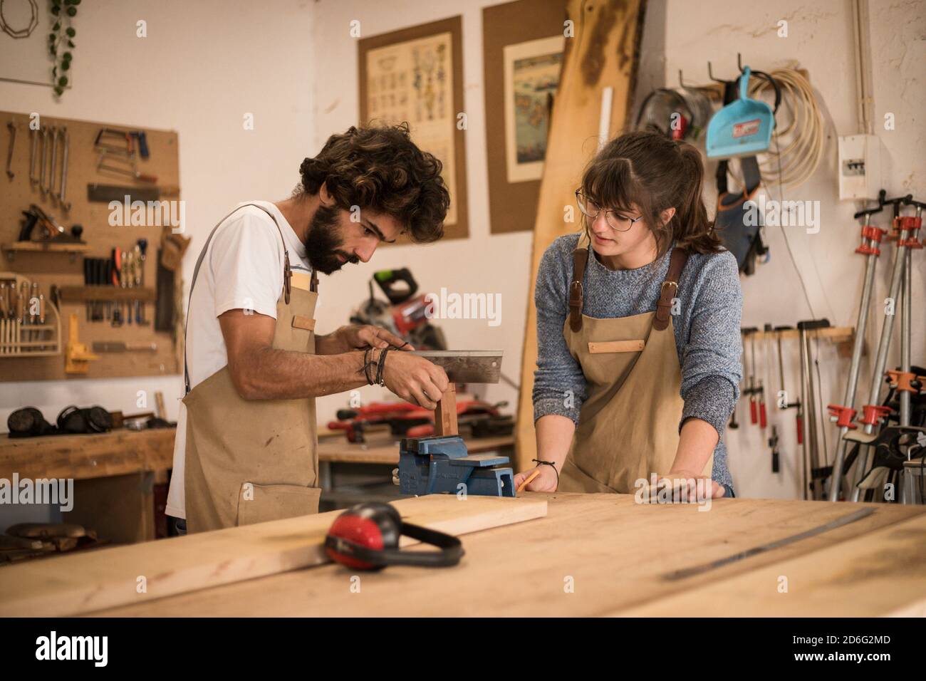 A young couple of carpenters working together in a small carpentry ...