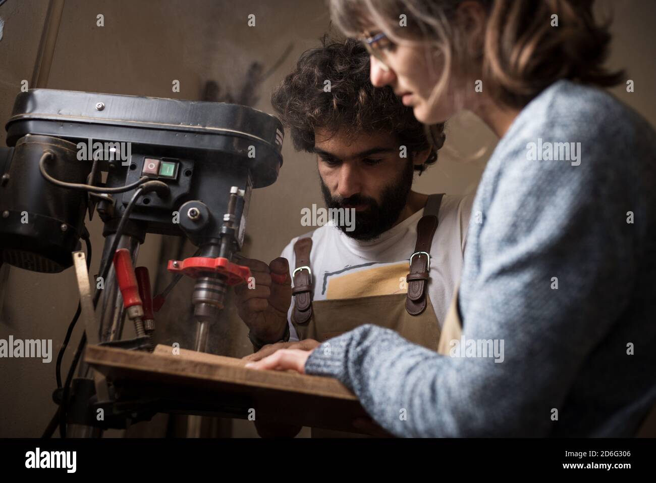 A young couple of carpenter working together in a small wood laboratory ...