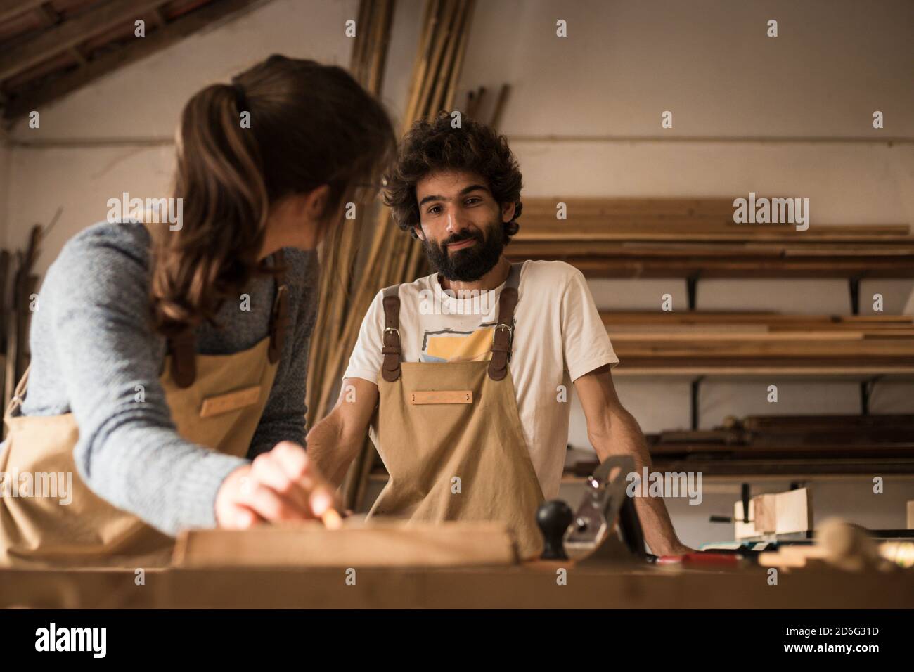 A young couple of carpenters working together in a small carpentry ...